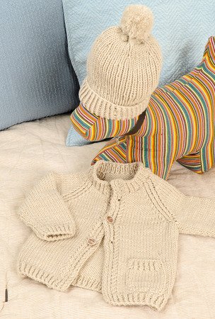 Beigefarbene Jacke und rosafarbener Pulli mit Mütze